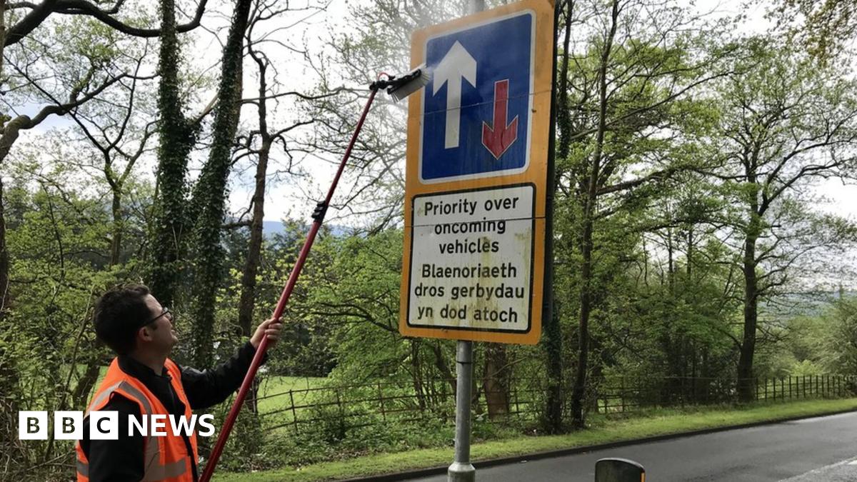 Window cleaner Kieran Benson scrubbing Glynneath road signs - BBC News