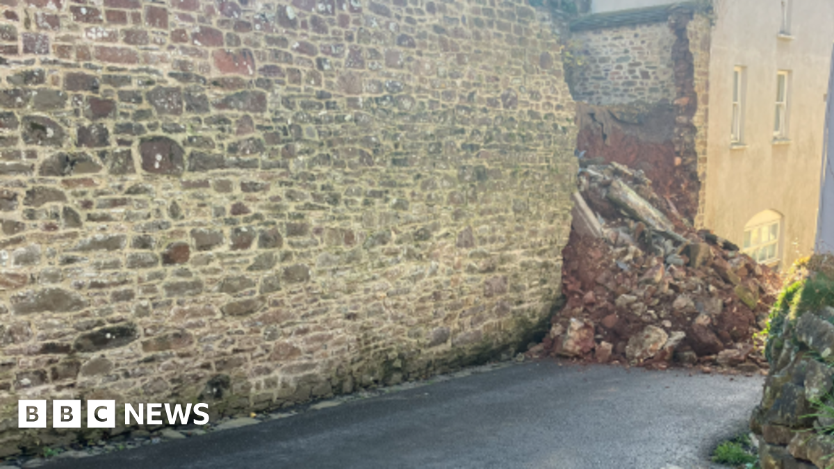 Diversions after 12ft wall collapses into Devon town road - BBC News