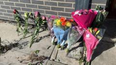 Tributes left as teen held over Luton tower block deaths - BBC News
