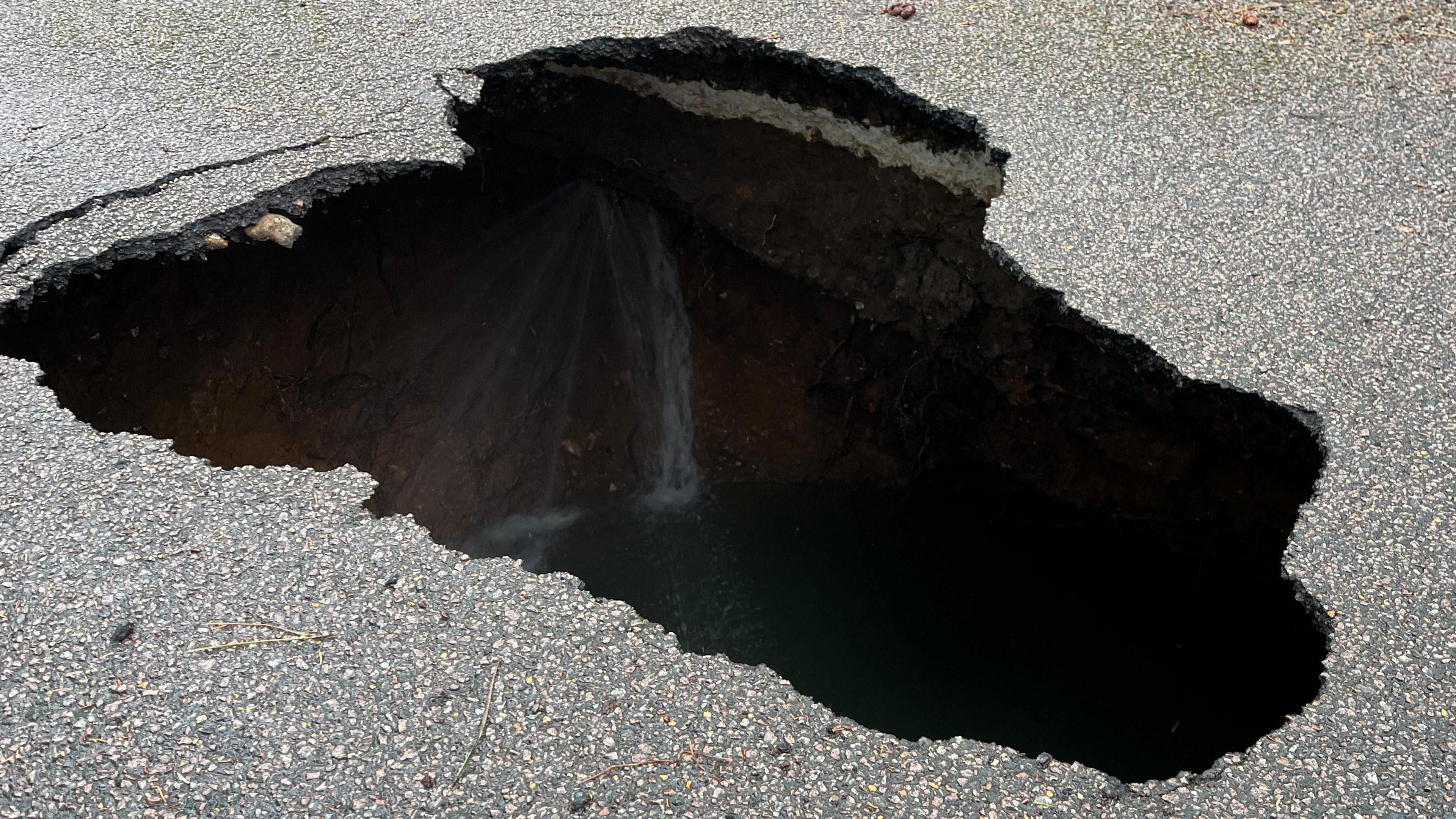 Still closed: Road in Harpenden with hole and burst water main - BBC News