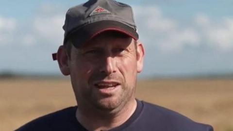 Farmer in cap with field behind him