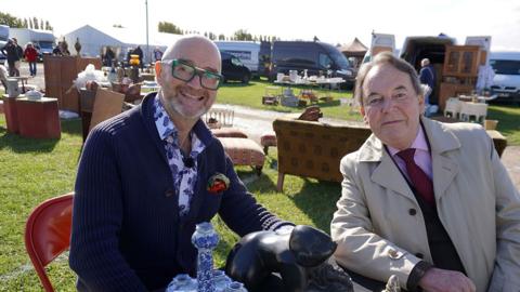 Bargain Hunt presenters smiling into the camera at a car boot sale