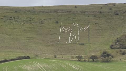 Long Man of Wilmington carving given face mask makeover - BBC News