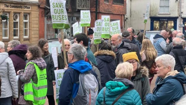 Dozens gather in Wiveliscombe to protest over bus cuts - BBC News