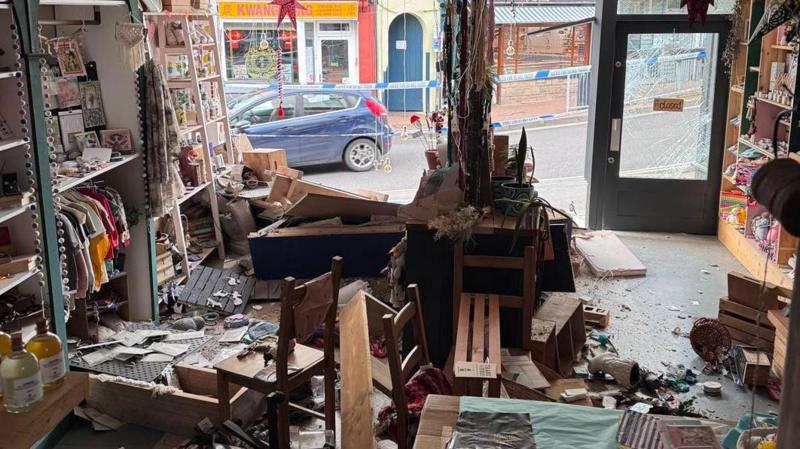 Oswestry retailer 'devastated' after car crashes into shop - BBC News