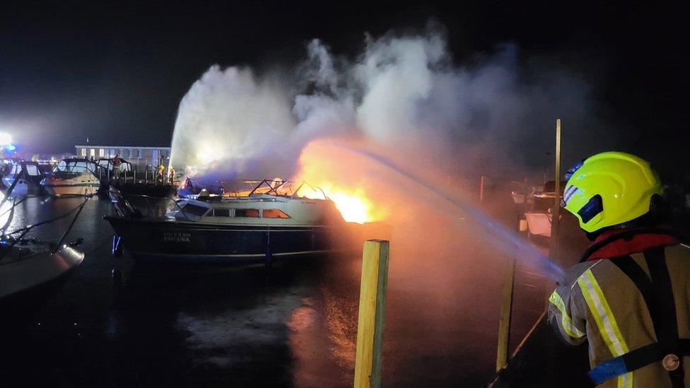 Crews tackle fire involving three boats in Oulton Broad - BBC News