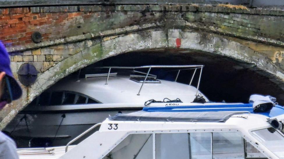 Boat freed after getting stuck under Wroxham bridge - BBC News