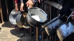 የማብሰያ ድስት ይዘው የተሰለፉ ሰዎች