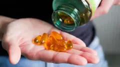 Des capsules de vitamine D dans la main d'une personne