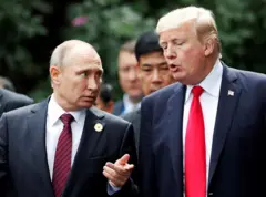 Trump e Putin conversando em área externa, com árvores e assessores atrás
