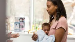 አራስ እናት ልጇን ታቅፋ መድኃኒት ይዛ