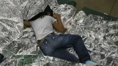 Una niña centroamericana duerme en el suelo, sobre una manta térmica plateada, en un centro de detención de la Patrulla Fronteriza de Estados Unidos en McAllen, Texas, el 8 de septiembre de 2014. (Foto: John Moore/Getty Images)