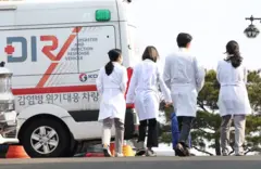 감염병 위기 대응 차량과 의사 가운을 입은 네 명의 의료진의 뒷모습