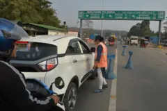 पूर्वी नेपालस्थित नेपाल भारत सीमा क्षेत्रमा एक जना महिला सेतो कारलाई जाँच गर्दै। भारतको अध्यागमनस्थित प्रवेशद्वारबाट सिटी रिक्सा र अन्य गाडीहरू आवतजावत गरिरहेका छन् 