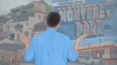 A composite image featuring a man facing away, holding his hands in the air. The left panel shows a typical Chinese village, to represent his hometown, the right panel shows a well-known environment for Chinese immigrants in the US. There is a sign for Monterey Park. 