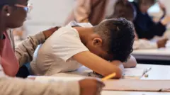 ፊቱን ጠረጴዛ ላይ የደፋ ተማሪ
