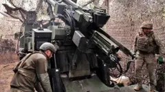 Two men load a Caesar gun near the front line in Ukraine