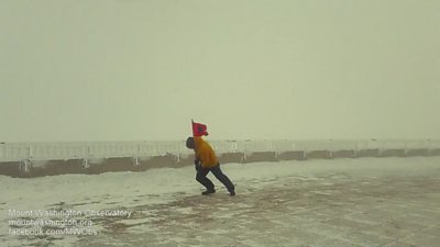 Man struggles to stand in 100mph winds - BBC Weather