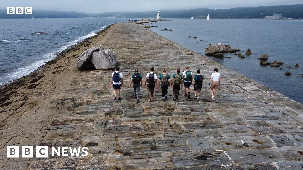 Students finish coast path walk on Plymouth breakwater - BBC News