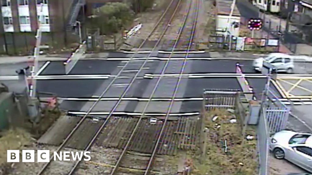 Footage reveals car swerving across rail tracks - BBC News