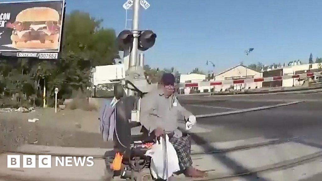 California officer saves man stuck on train tracks in wheelchair - BBC News