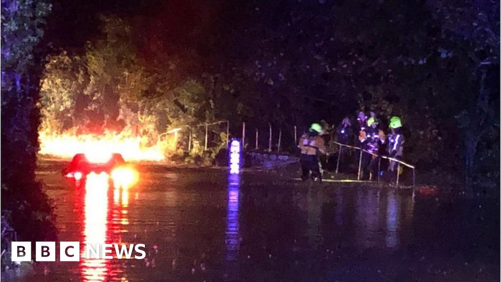 Four people rescued from car stuck in flood water - BBC News