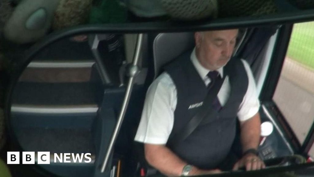 Driver on phone at wheel of holiday coach