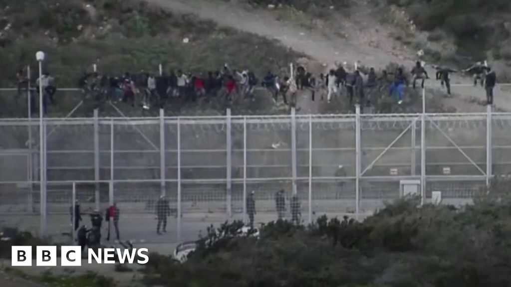 Migrants storm border fence at Spanish enclave - BBC News