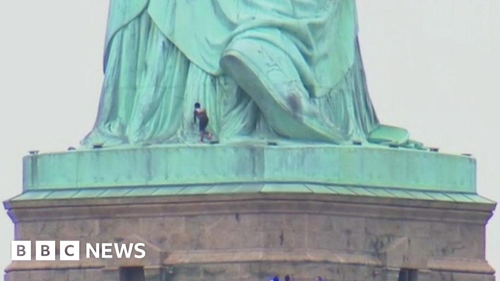 Person climbs to Statue of Liberty base - BBC News