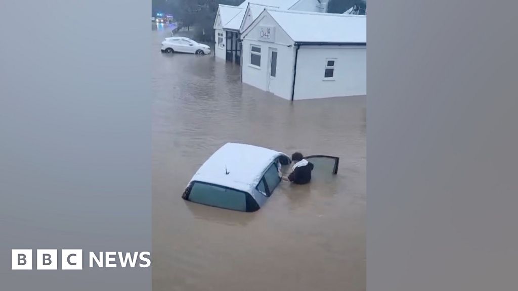 Man rescues woman stranded in flooded car - BBC News