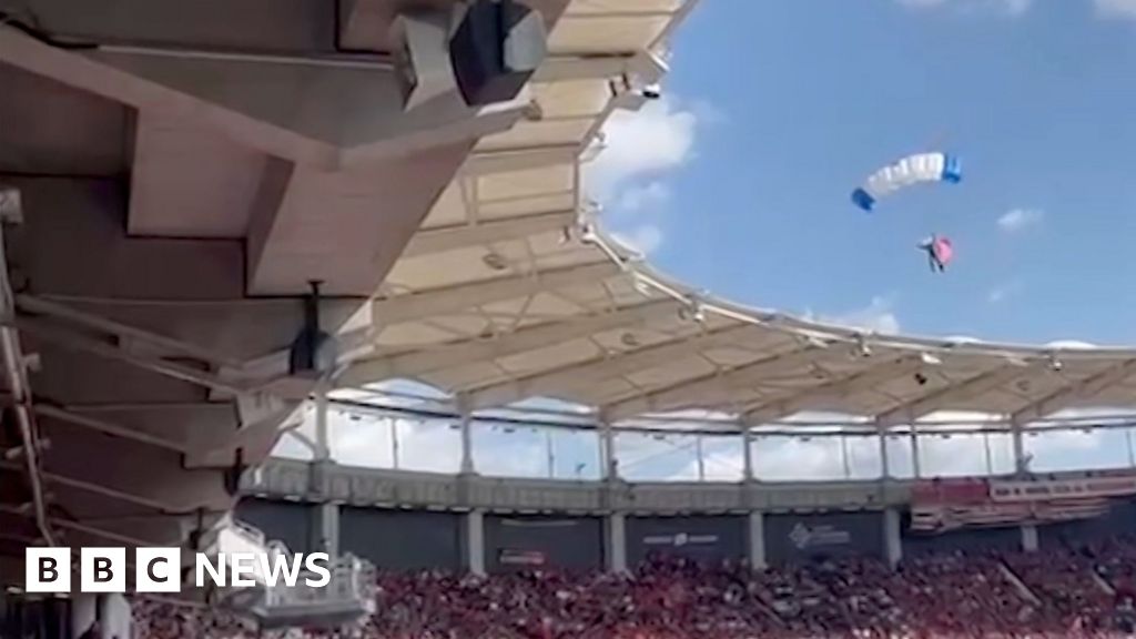 Moment parachutist left dangling on rugby stadium roof - BBC News