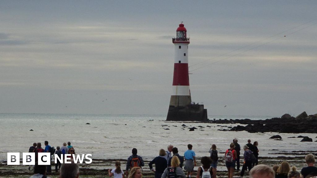 Eastbourne: Walkers trek around lighthouse during rare low tide - BBC News