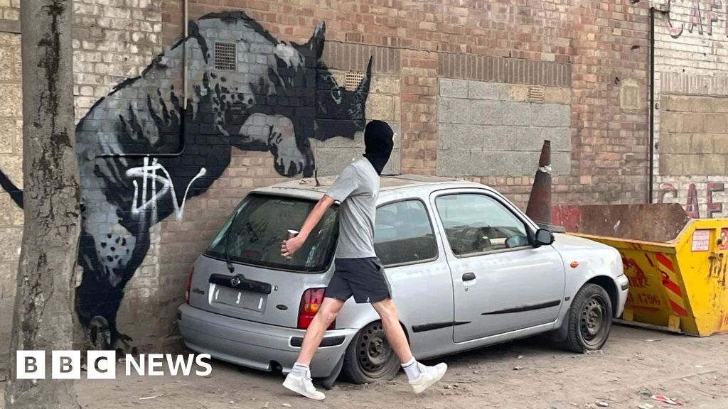 Moment Banksy rhino artwork is defaced by man in balaclava - BBC News