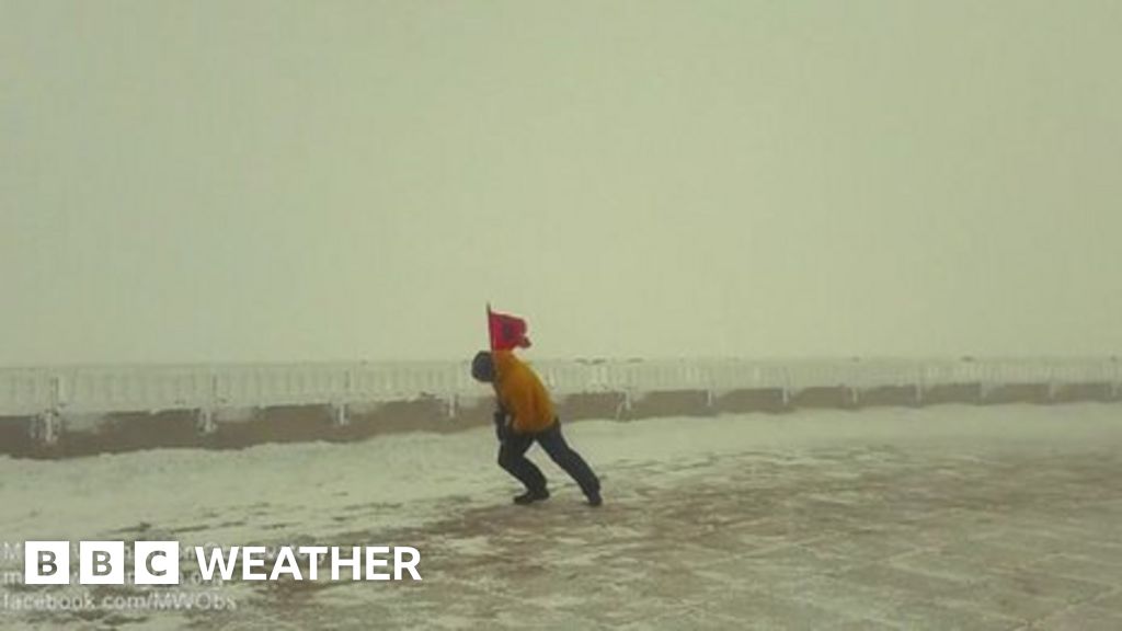 Man struggles to stand in 100mph winds - BBC Weather