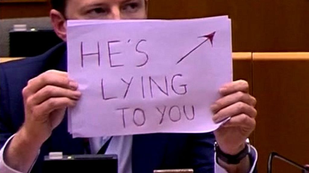 'He's lying' sign held behind Nigel Farage - BBC News