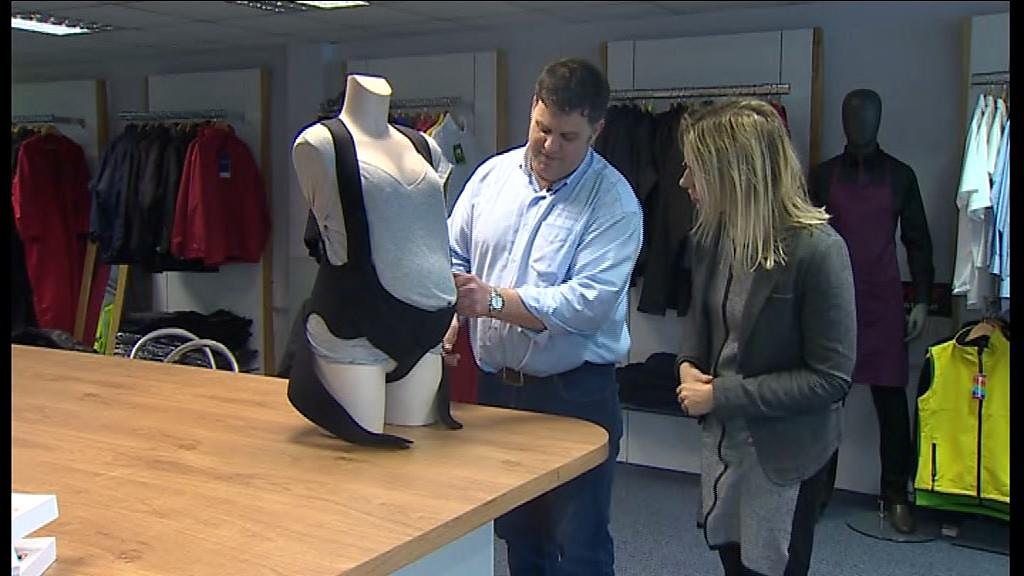 Dafydd Roberts yn dangos y ddyfais i Elen Wyn - BBC Cymru Fyw