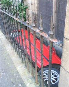 Car wedged down side of building - BBC News