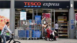 Tesco full-year pre-tax profits hit by fine - BBC News