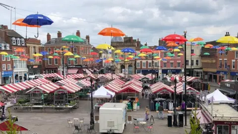Hundreds of brightly-coloured umbrellas appear above market