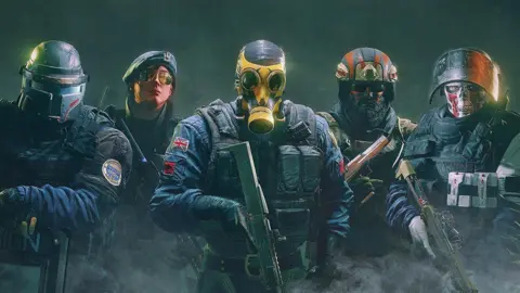 A promotional picture for Rainbow Six Siege featuring 5 soldiers looking into the camera from different militaries. The UK one is front and centre wearing a yellow gas mask and carrying a shotgun. 