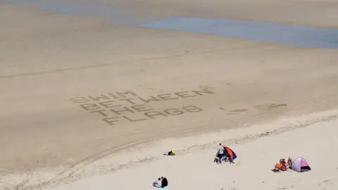 Safety messages written in the sand on Cornish beaches