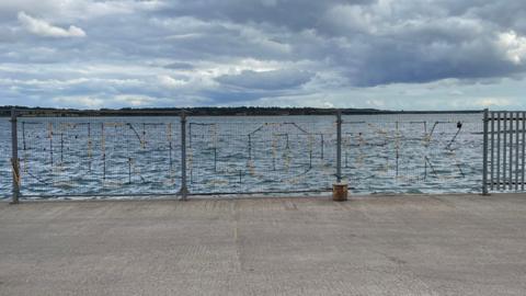 Mistley Quay campaigners chain 'eyesore' fencing in 14-year row - BBC News