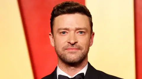 Justin Timberlake poses on the red carpet in a tuxedo