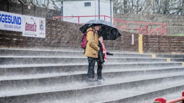 Workington Reds fans snapped smiling in a downpour - BBC News