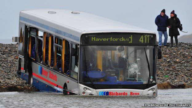 Driver of bus hit by wave defends decision to cross road - BBC News
