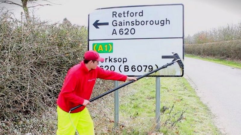 Window cleaner Kieran Benson scrubbing Glynneath road signs - BBC News