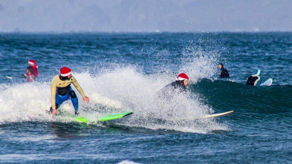 Newquay surfers dress as Santa to ride waves for charity - BBC News