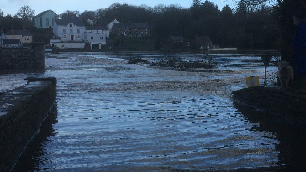 Bridge submerged as flooding affects parts of Wales - BBC News