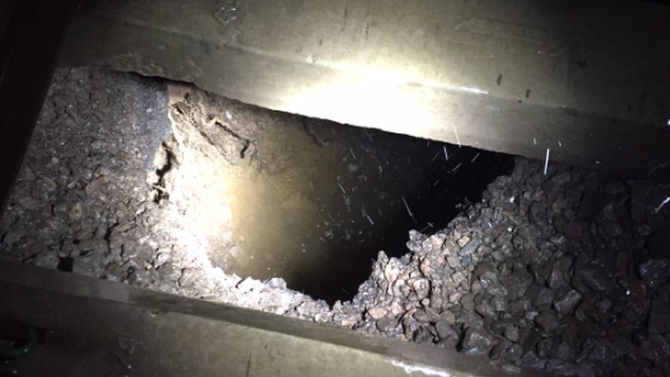 Rail line repaired after floods leave 6ft hole under track - BBC News