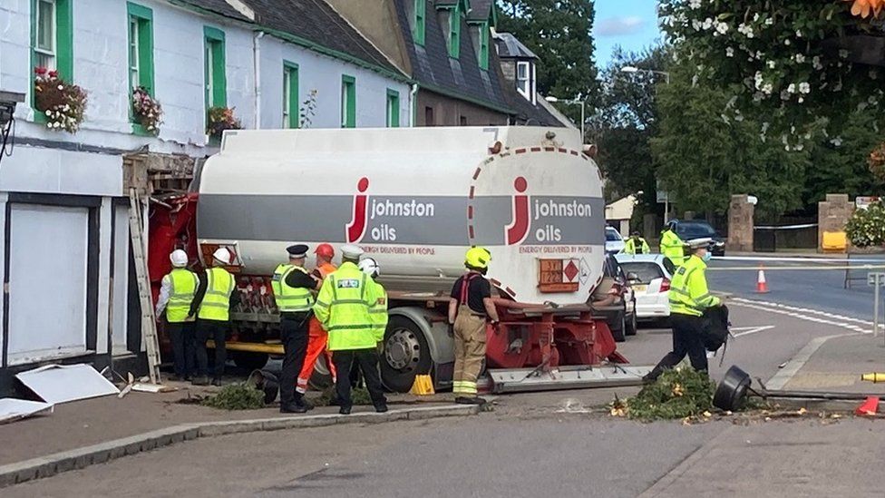Oil tanker crashes into car and building in village - BBC News